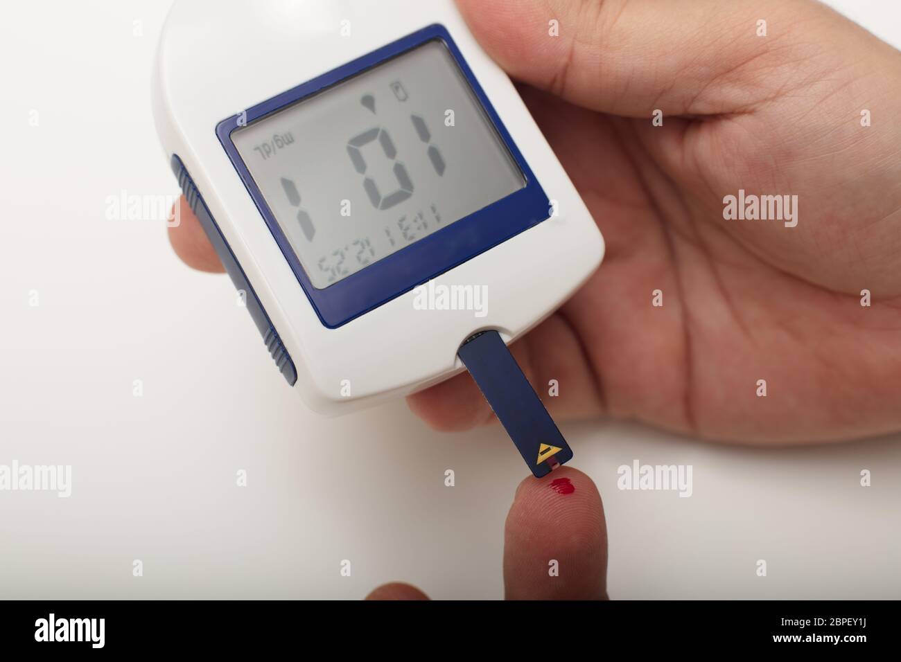Man with diabetes using a portable digital glucose meter drawing up a ...