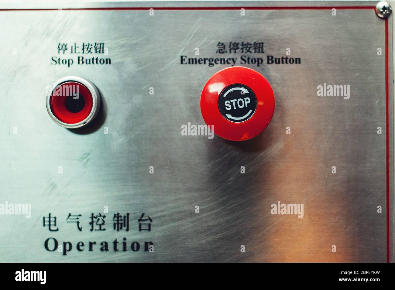 red emergency stop button, inscriptions in English and Chinese Stock ...