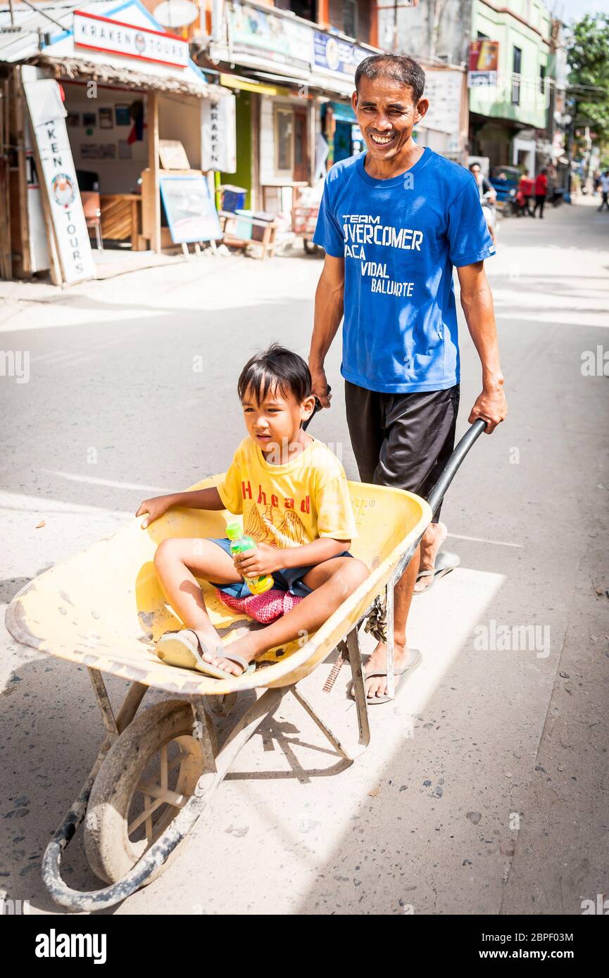 A cute little filipino boy gets a lift in a wheelbarrow along the ...