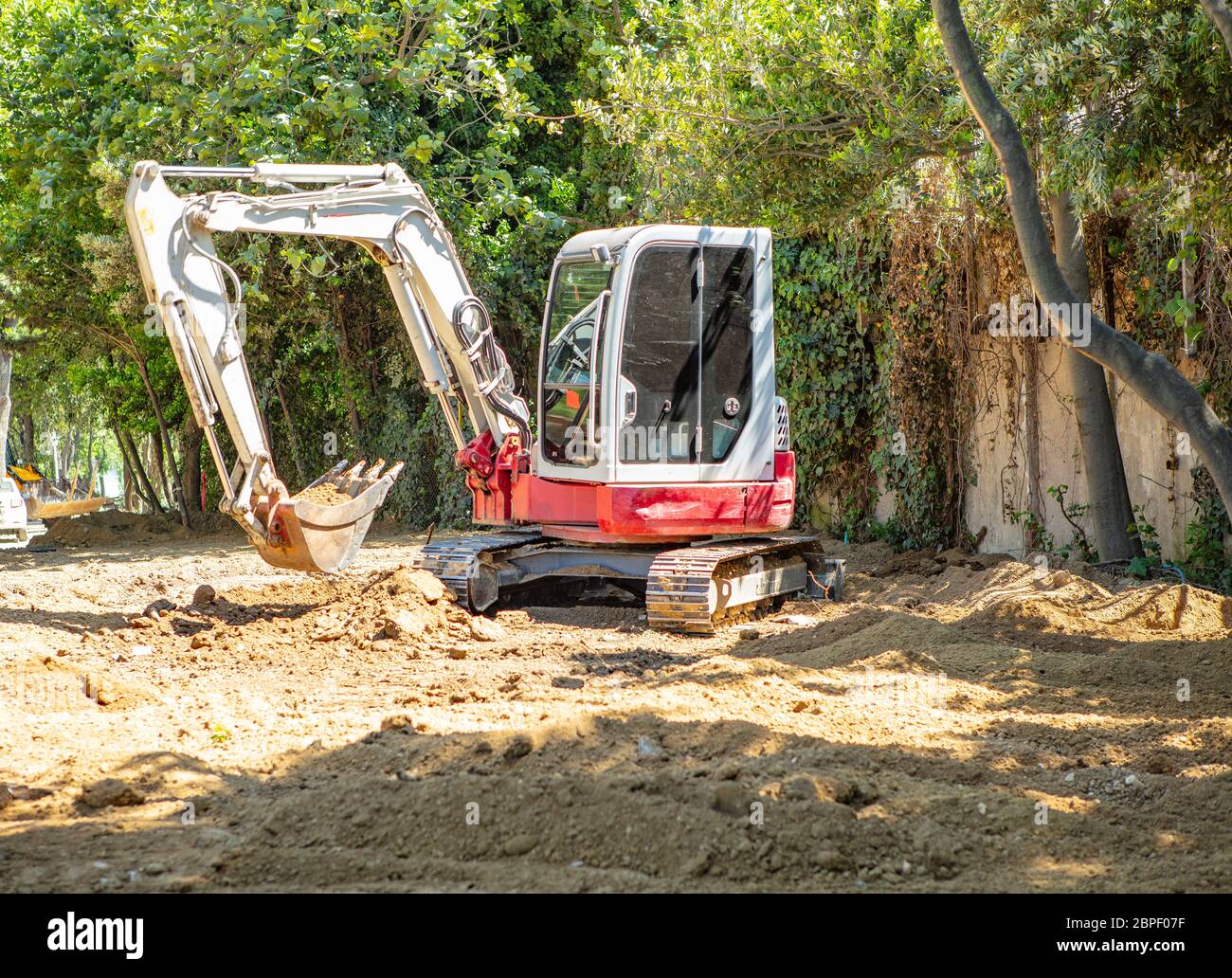 Excavator, backhoe working on soil for clear the area beside trees for ...