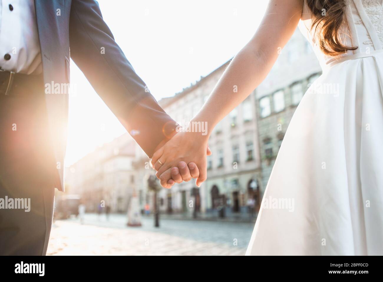 Wedding couple holding hands on sunset background Stock Photo - Alamy