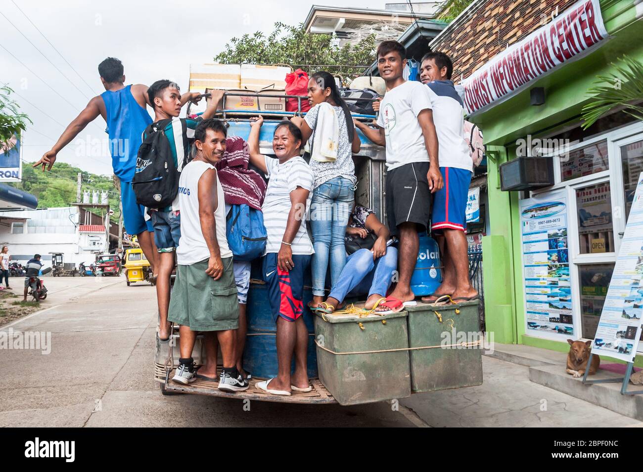 A bunch of local filipino people cling to the back of a bus as it ...