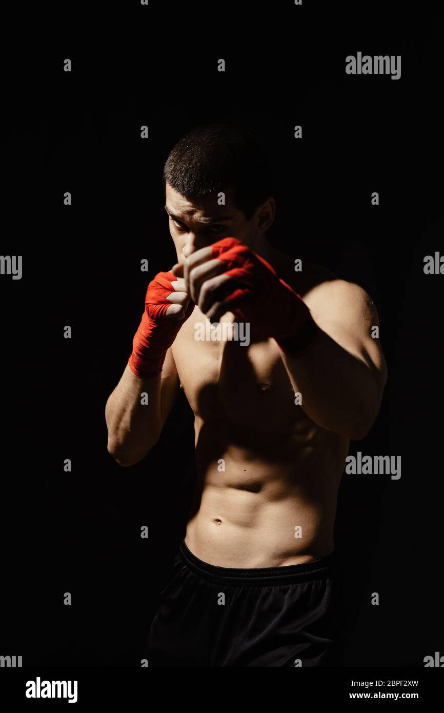 Athletic boxer punching with determination and precaution over black ...