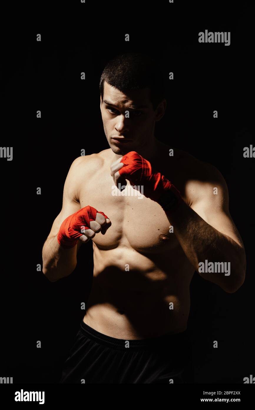 Athletic boxer punching with determination and precaution over black ...