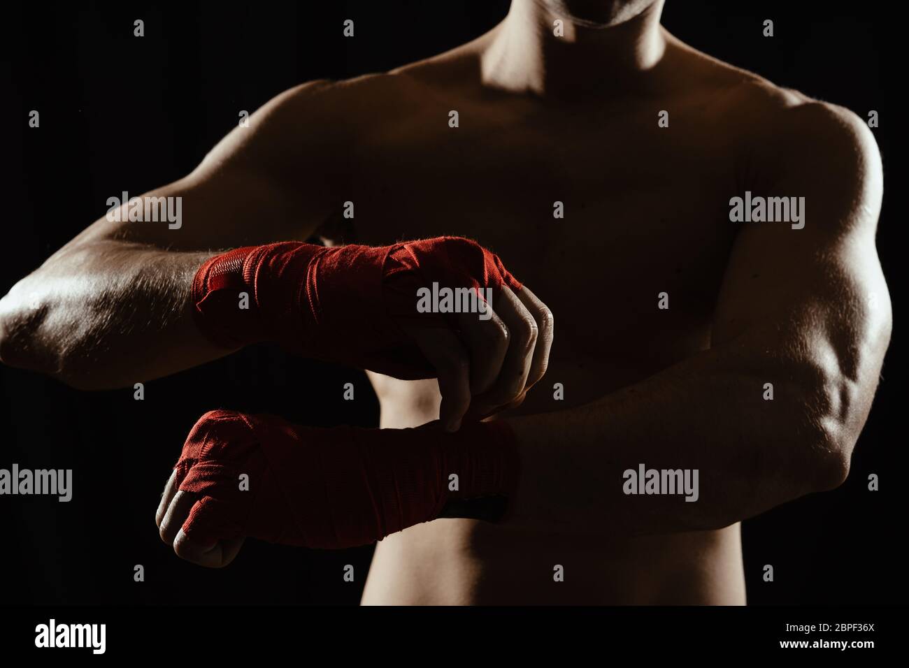 Close-up of the hands of a young boxer who winds red bandages before a ...