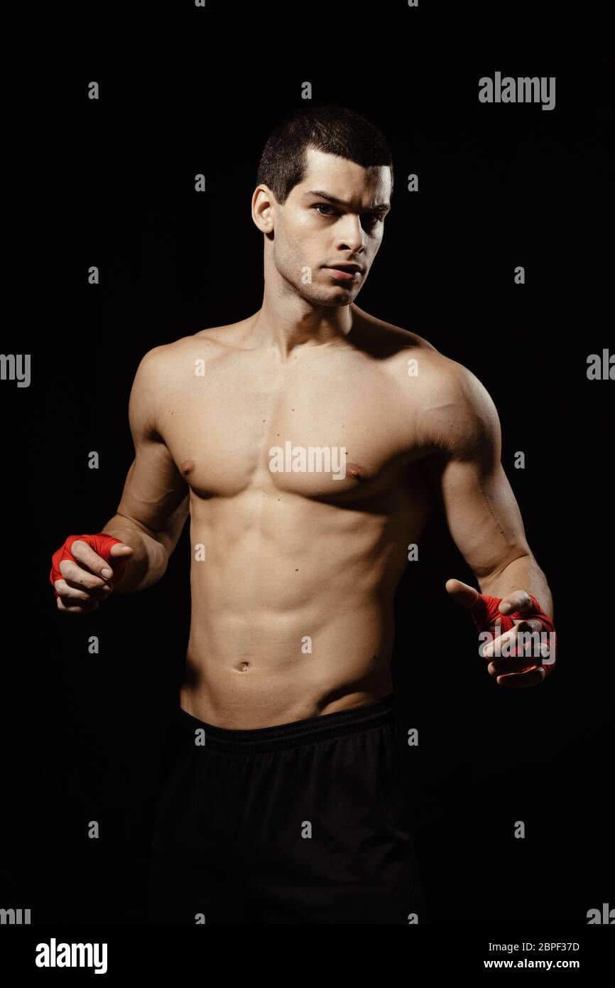 Portrait of male boxer posing in boxing stance against black background ...