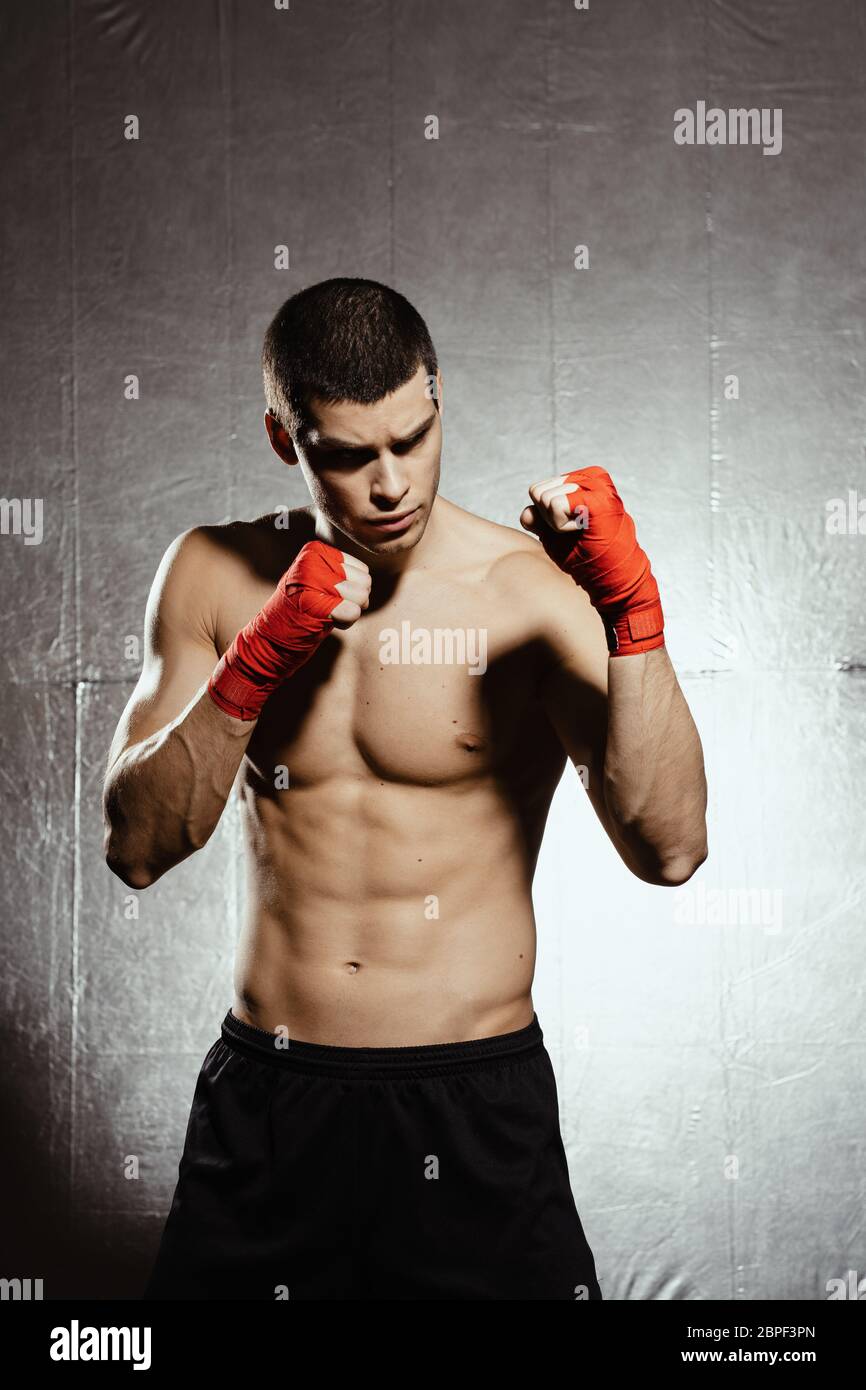 Boxing male portrait standing in a rack on black background with red ...