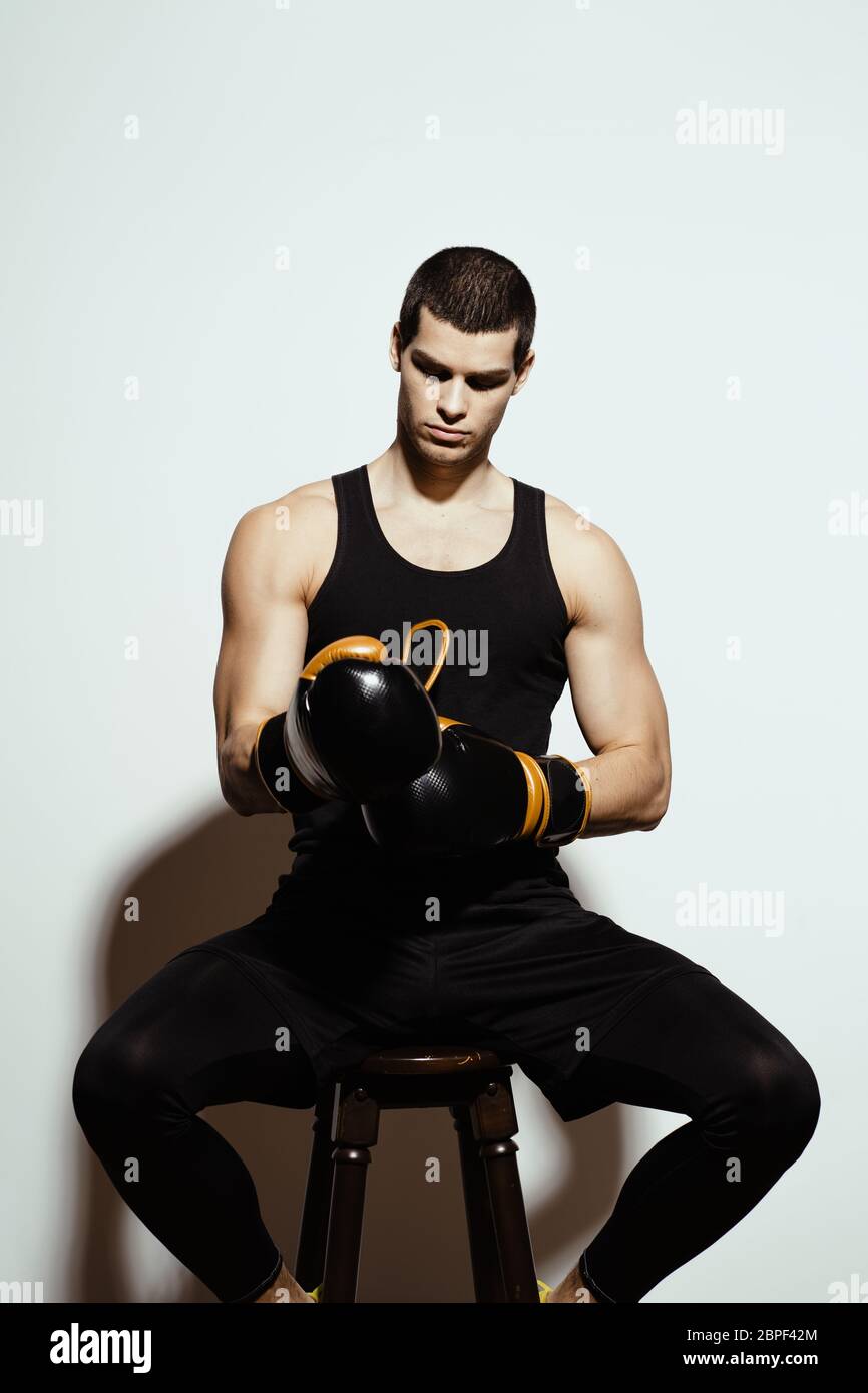 Boxer putting on his boxing gloves while resting on the chair on the ...