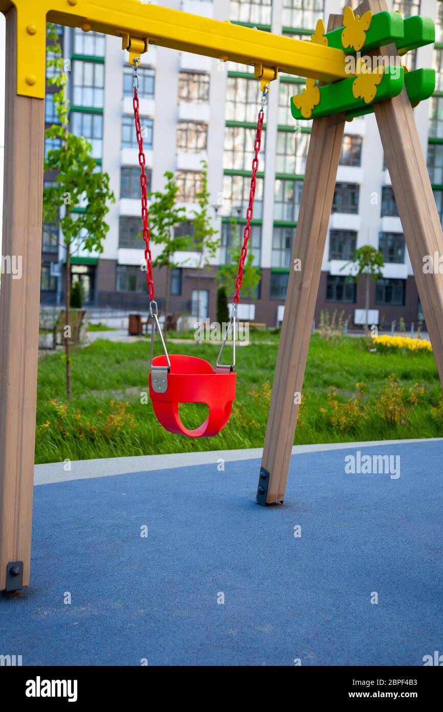 Empty chain swing in playground. Children park with red swing for baby ...