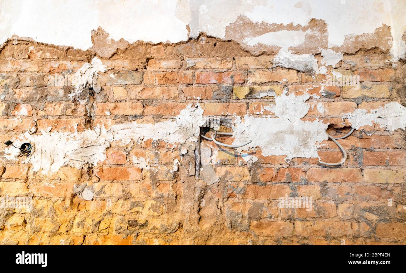 Brick wall with holes for power sockets and cables during a renovation ...