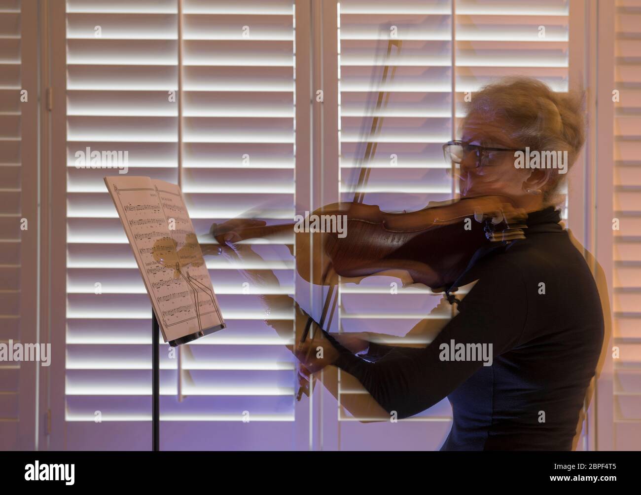 Standing woman playing classical violin against background of louvre ...