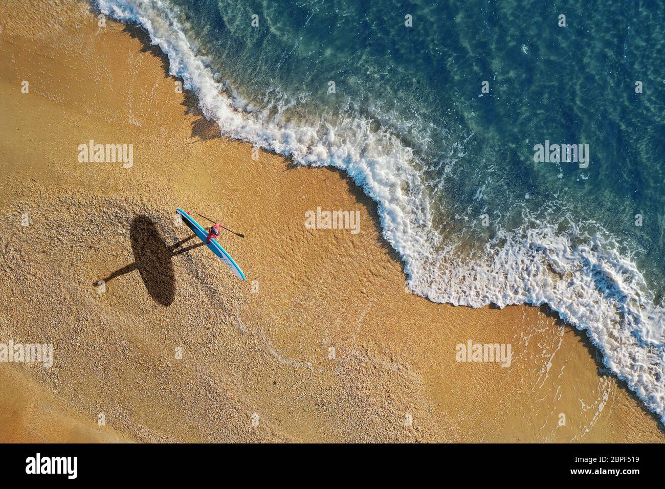 Aerial view of surfer on beach with paddleboard Stock Photo - Alamy