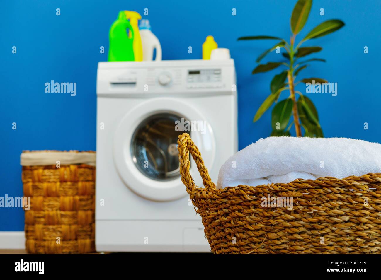 Washing machine with laundry on blue wall background Stock Photo - Alamy