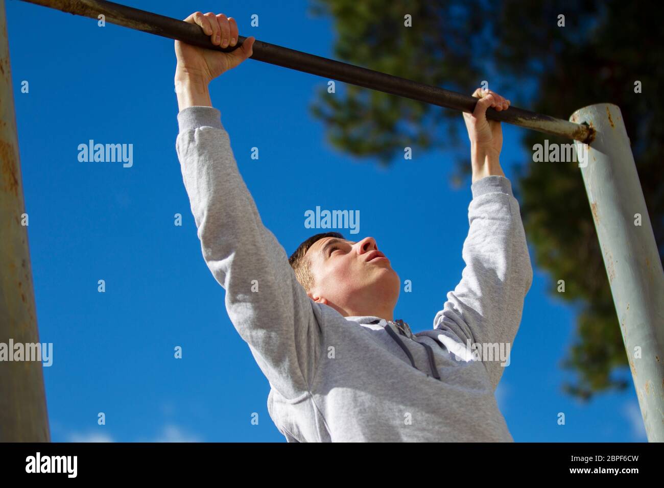The boy pulls himself up on the horizontal bar on the street. A young ...
