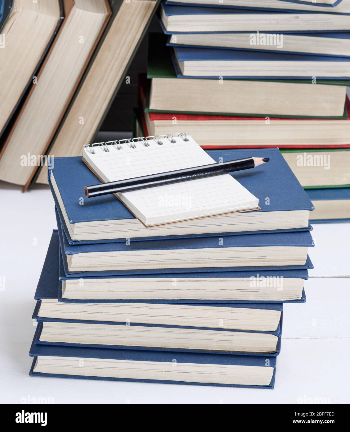 empty notebook with white sheets and a black pencil are on a stack of ...