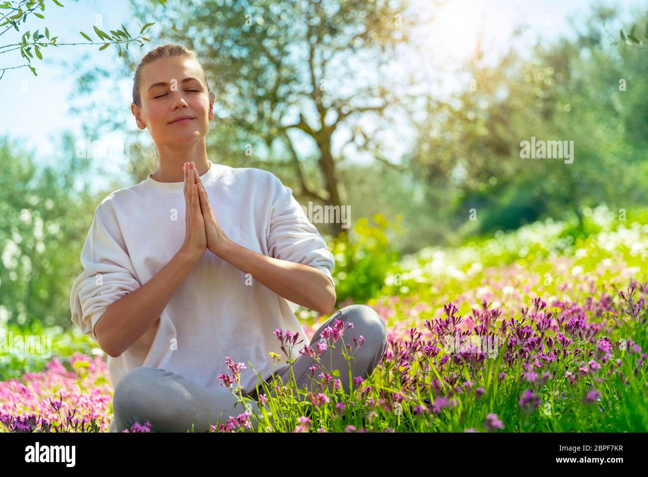 Beautiful woman doing yoga exercise outdoors, nice female in lotus pose ...