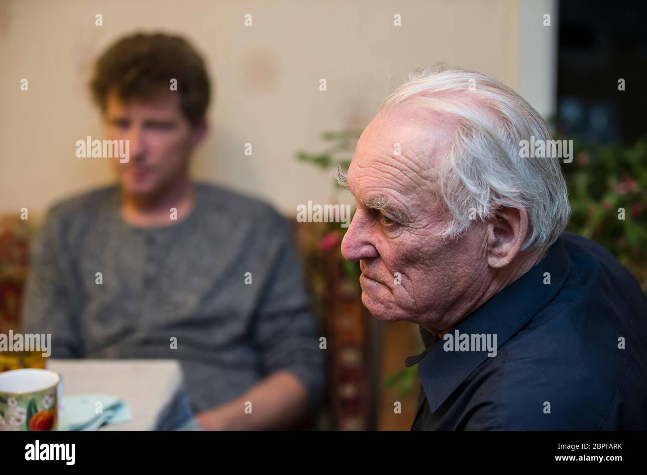 Old father on the background of an adult son. Father and son Stock ...