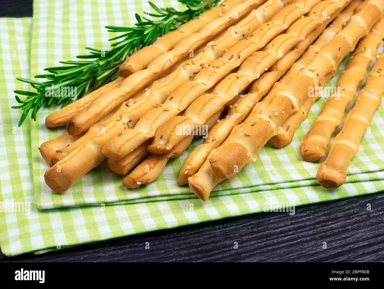 Crispy bread sticks with salt and rosemary on a checkered cloth on a ...