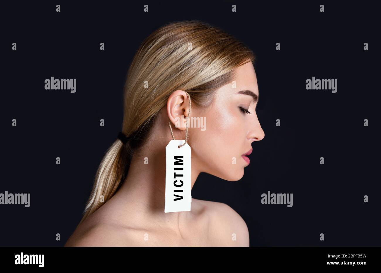 Portrait of girl expressing pain and sadness, label on ear is victim ...