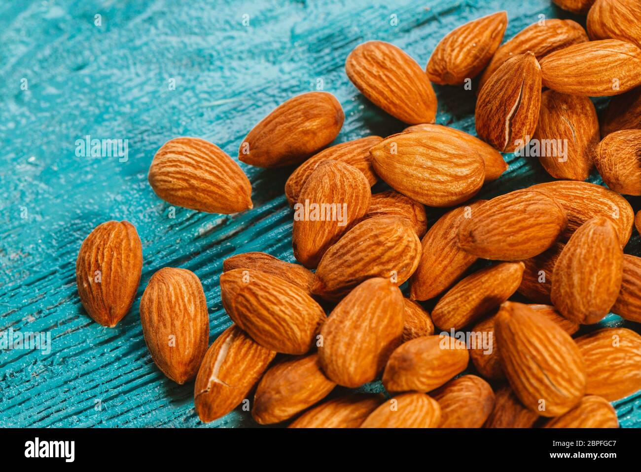 handful of almonds on a blue wooden background Stock Photo - Alamy