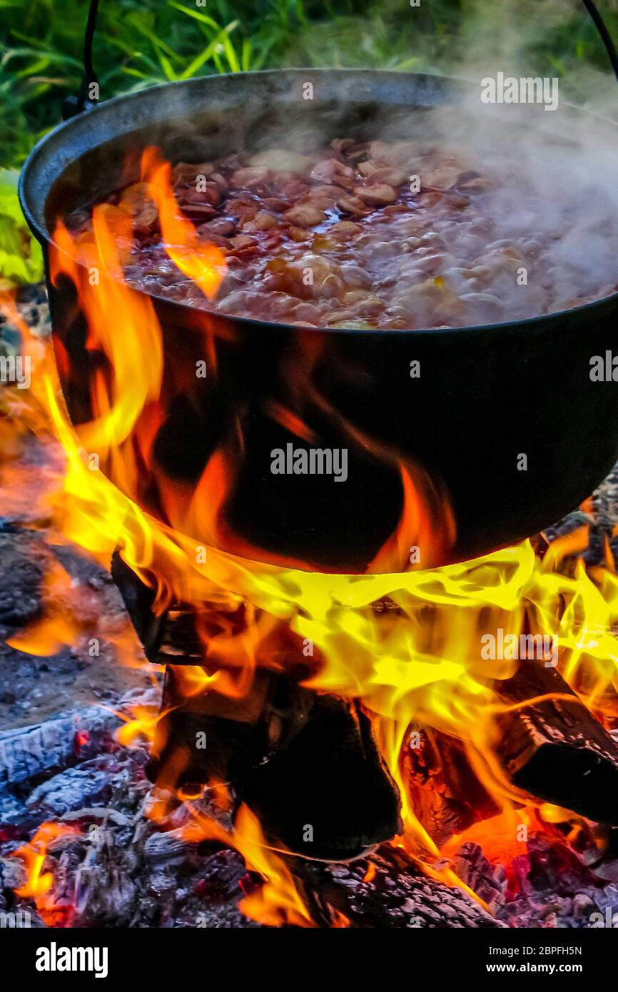 Cooking soup in cast iron boiler on burning campfire. Pot with soup ...