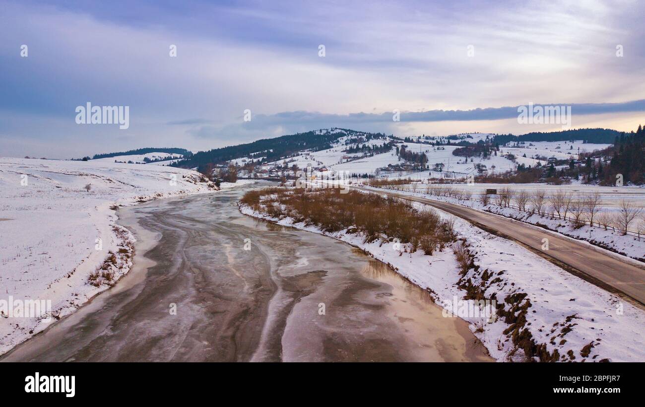 Frozen winter river. Aerial rural view of snowy village and road ...