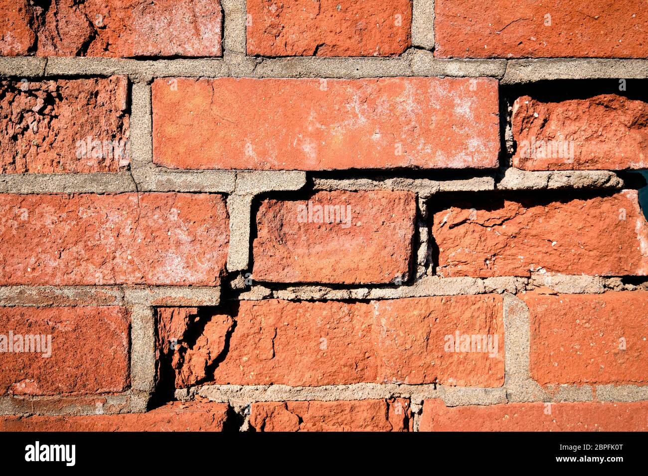 Close-up of an old decaying wall made of red bricks as background. Seen ...