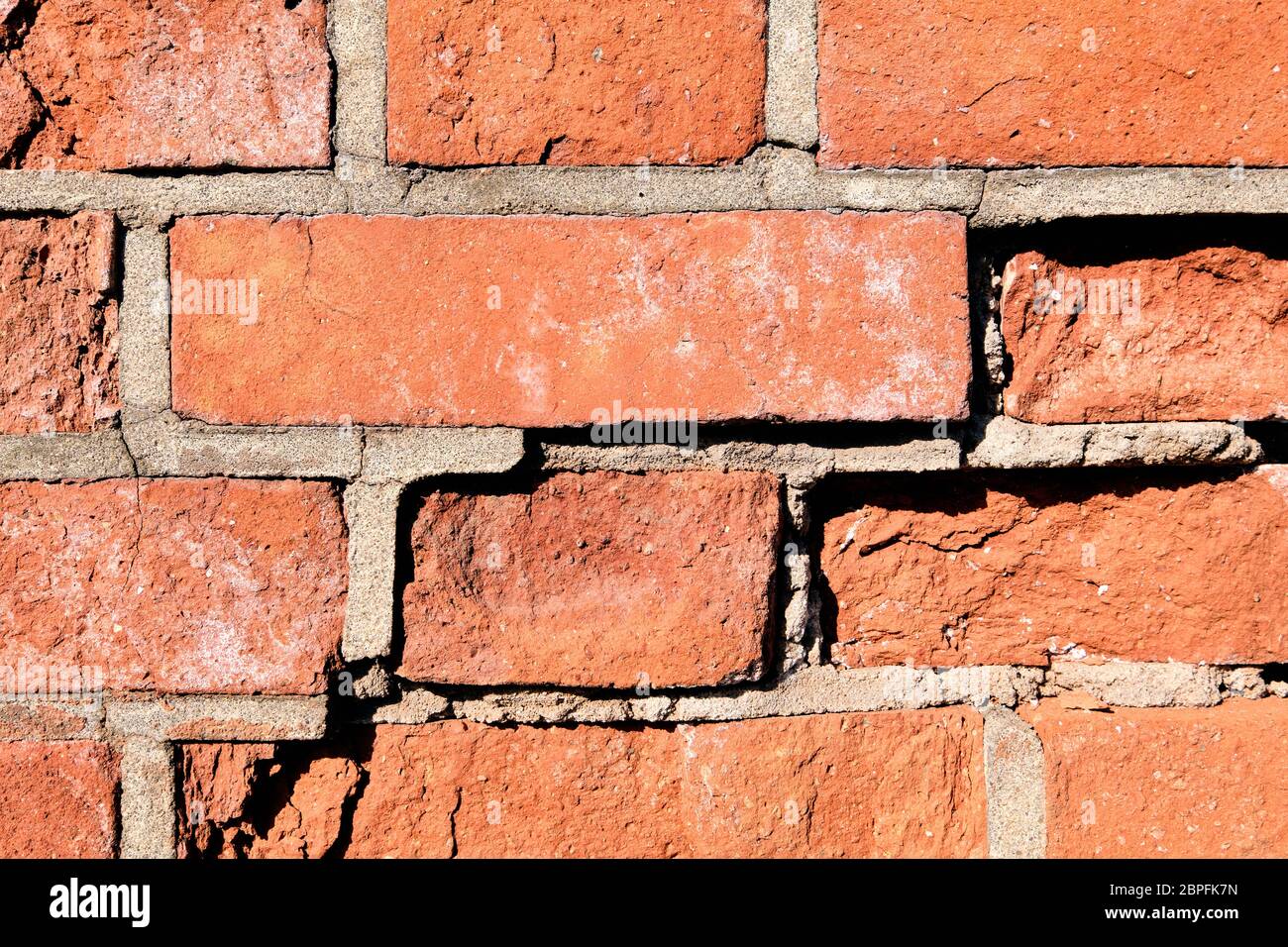 Close-up of an old decaying wall made of red bricks as background. Seen ...