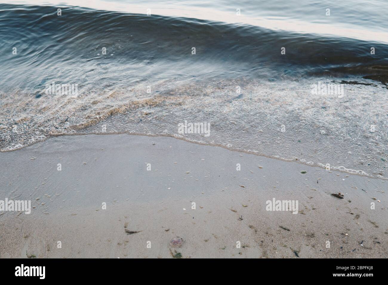horizontal view of small waves hitting on a sandy shore Stock Photo - Alamy