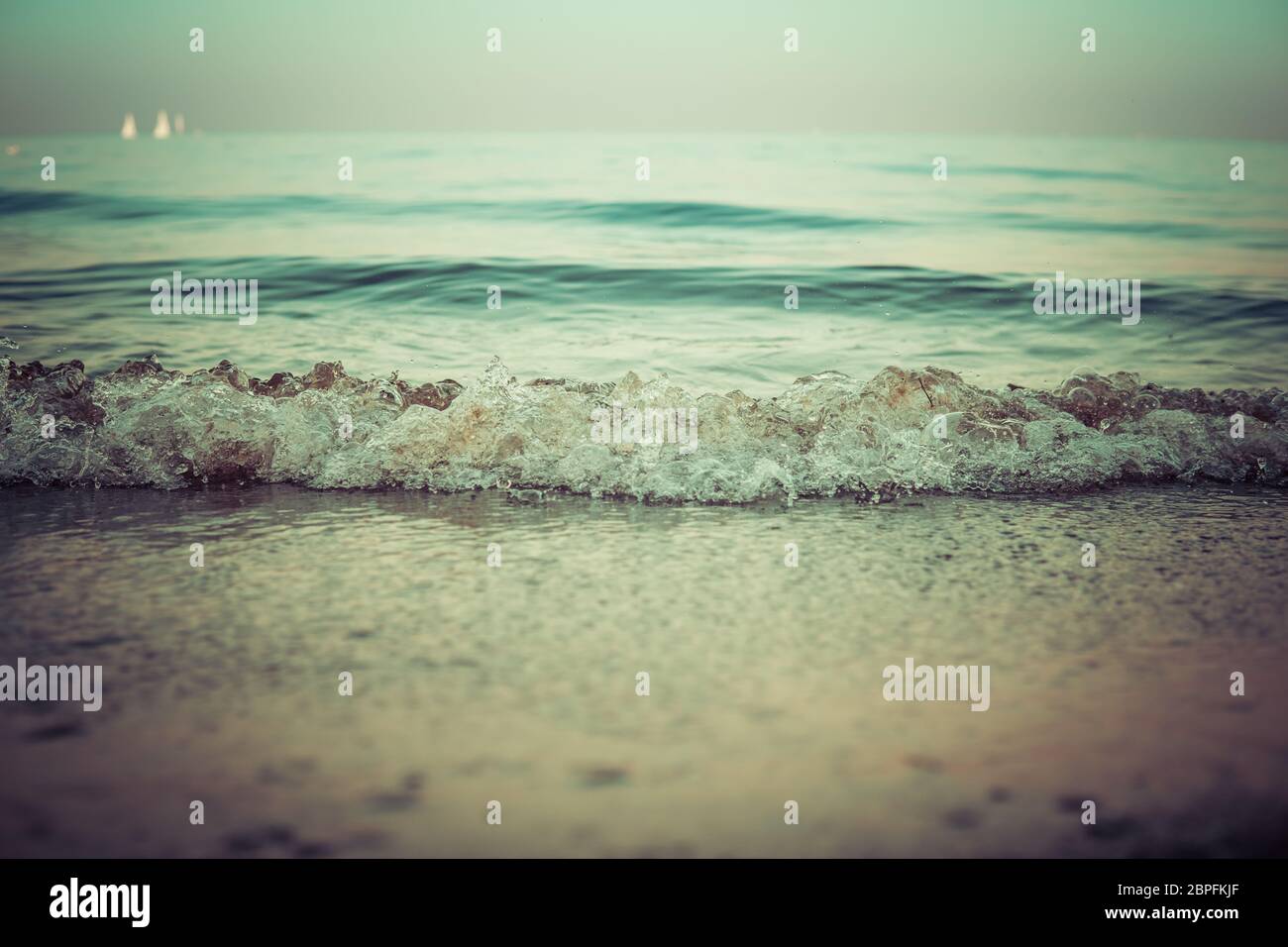horizontal view of small waves hitting on a sandy shore Stock Photo - Alamy