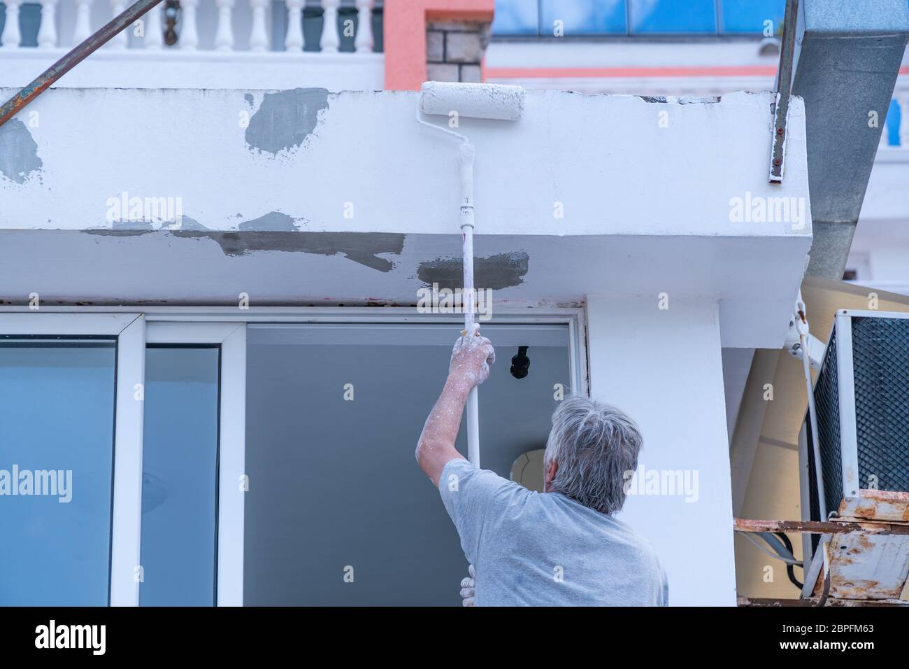 worker paints a building with white paint Stock Photo - Alamy