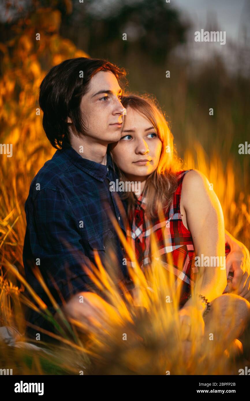 guy and the girl sitting in the grass on a sunset background Stock ...