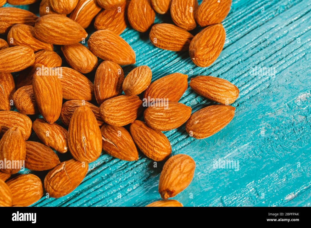 handful of almonds on a blue wooden background Stock Photo - Alamy