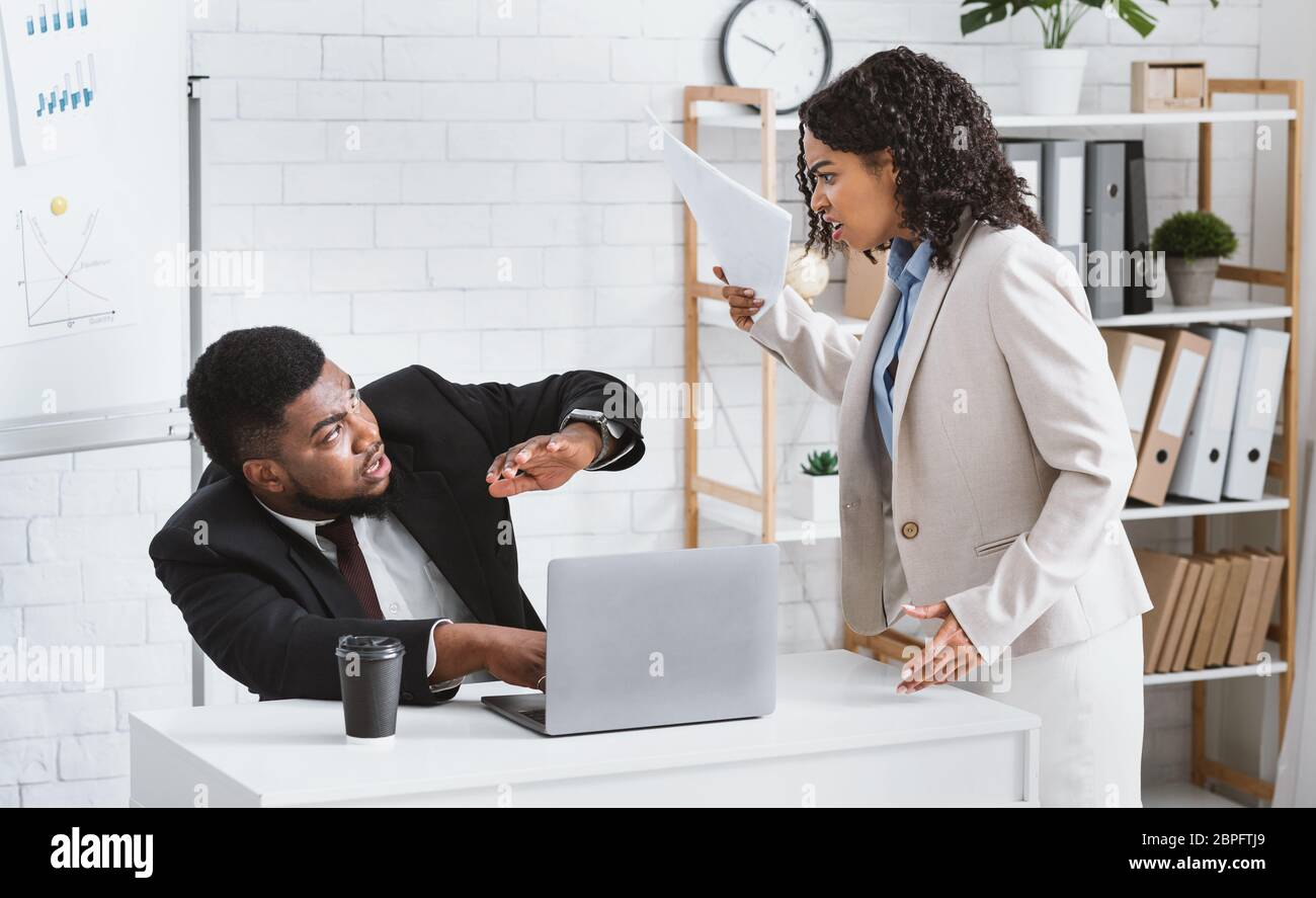 Upset lady boss with documents reprimanding young male employee at ...