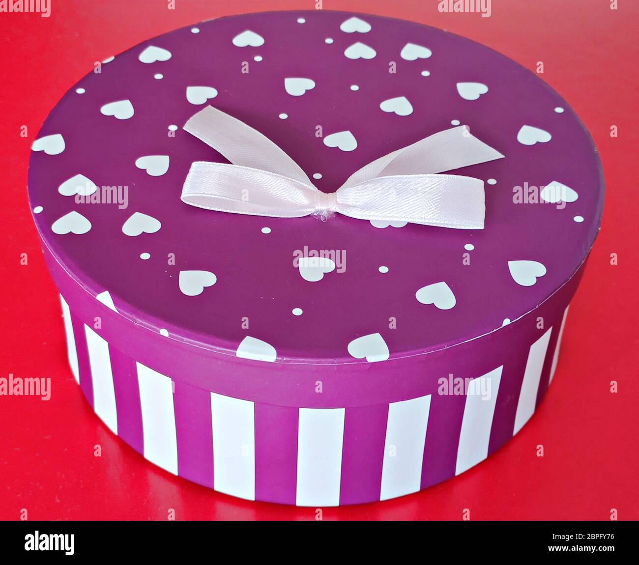 Purple gift box with circle striped box cover with purple ribbon and a ...