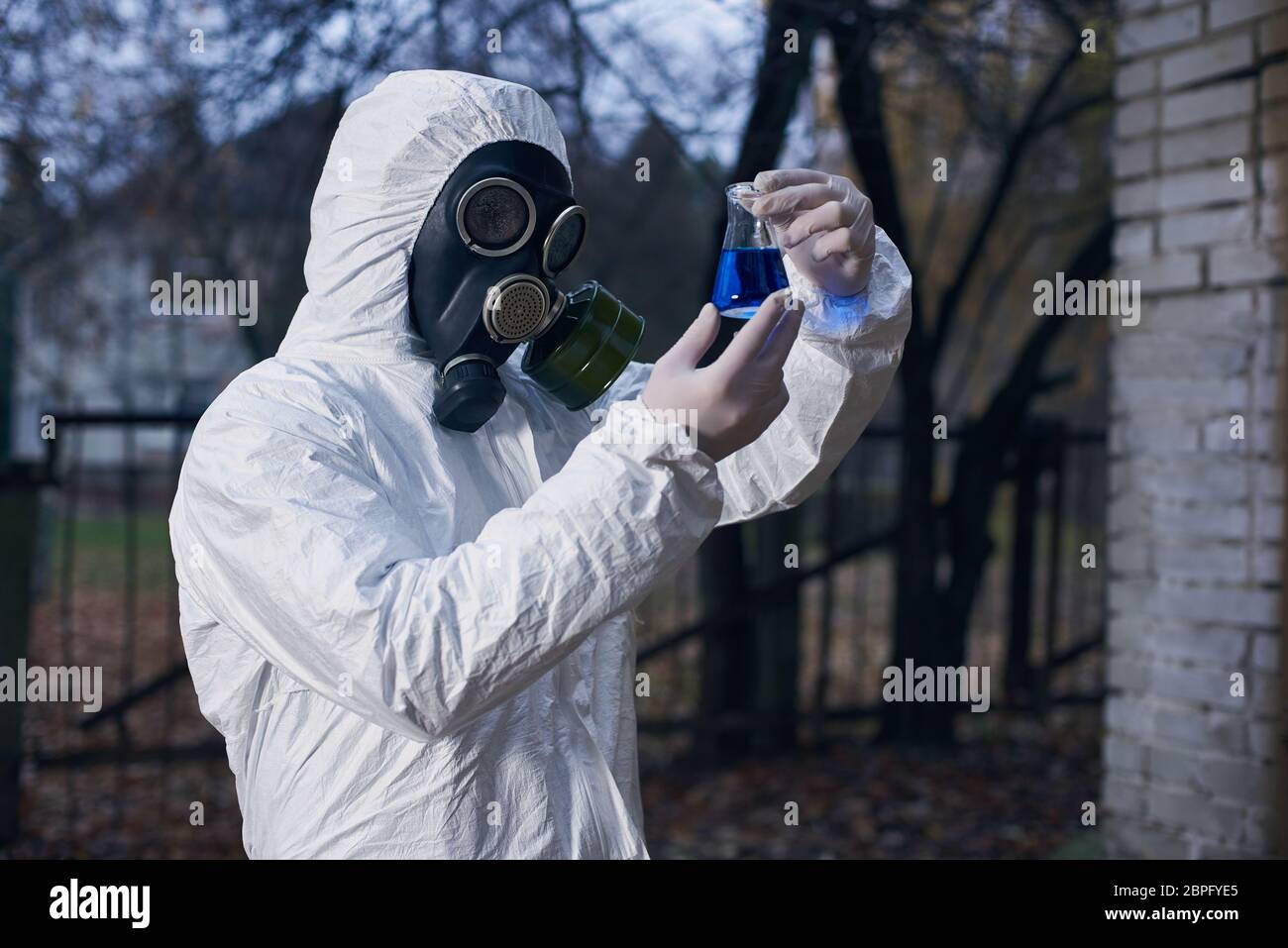 Scientist in protective suit and a gas mask, working in exclusion zone ...