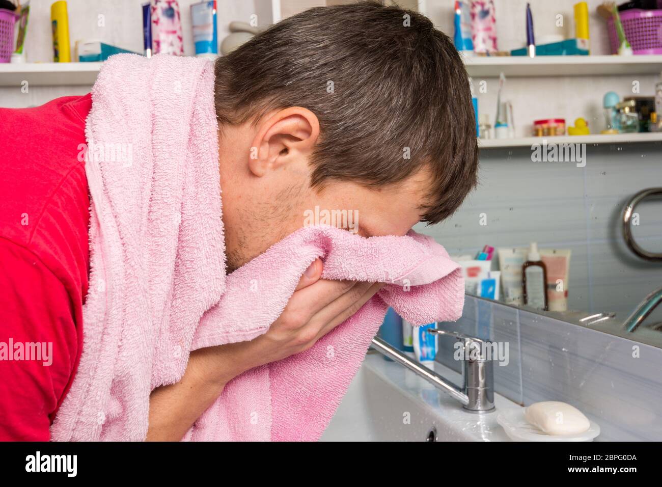 Man wipes his face with a towel in the bathroom Stock Photo - Alamy