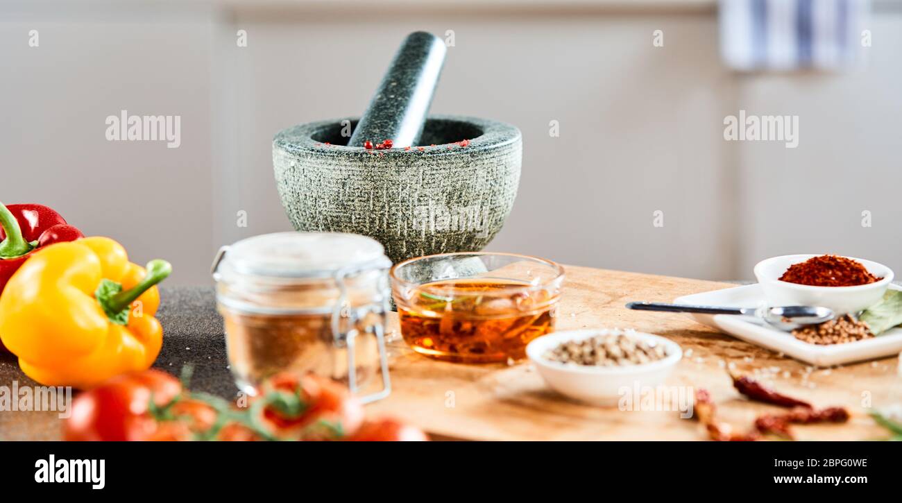 Stone pestle and mortar with oil and spices on a wooden kitchen board ...