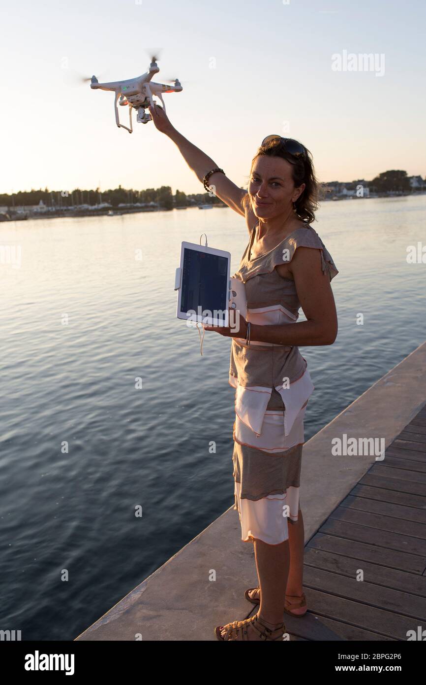 A female French photographer drone pilot stands on the dock in Etel and ...