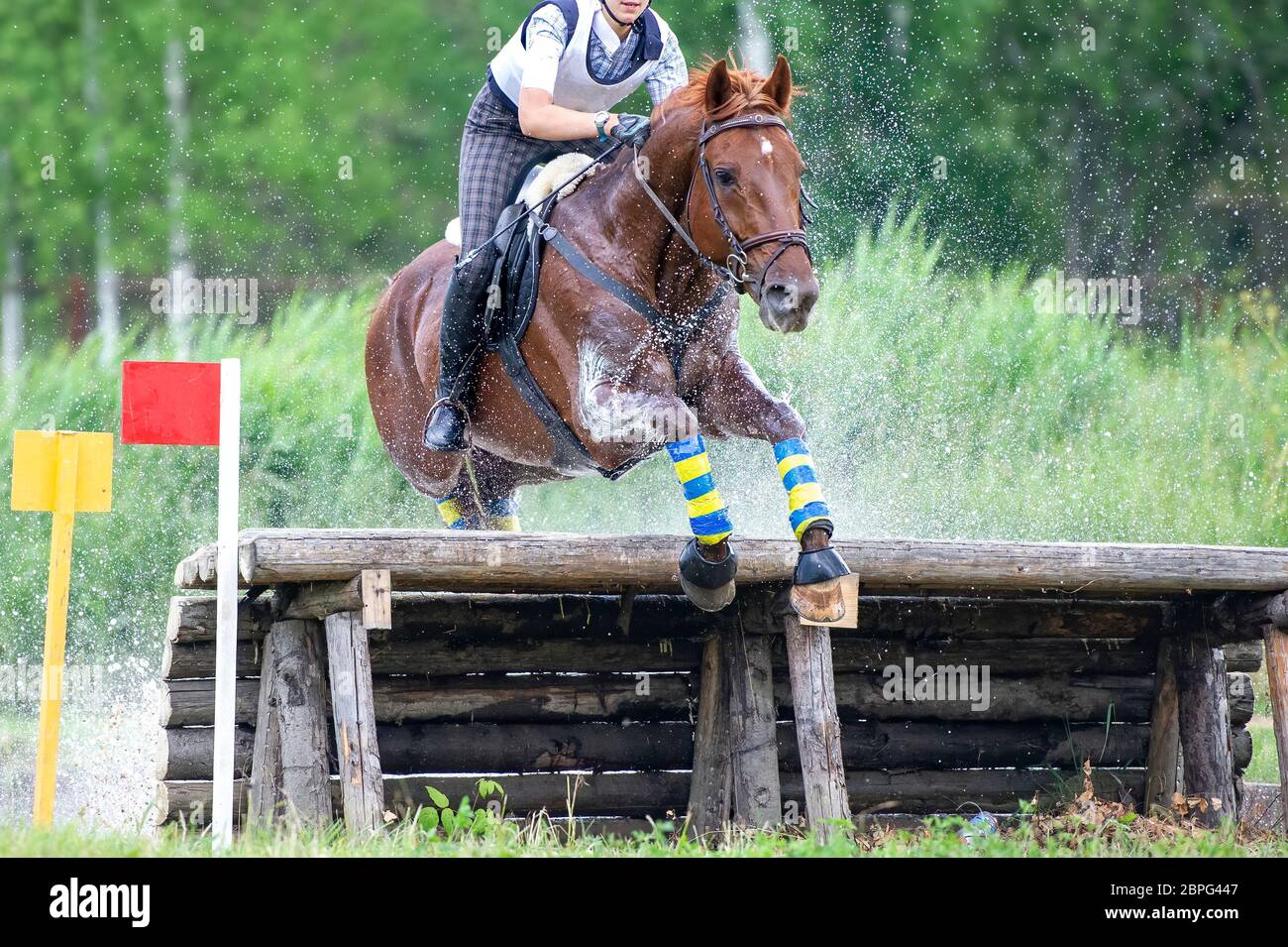 Eventing: equestrian rider jumping over an a log fence water obstacle ...