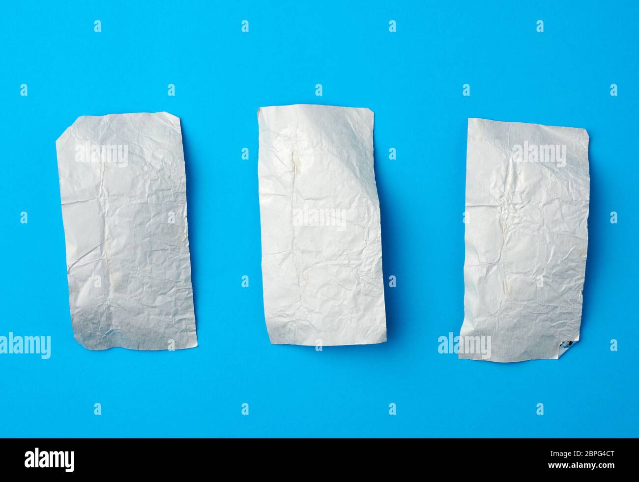 various crumpled foil used candy wrappers on a blue background, top ...