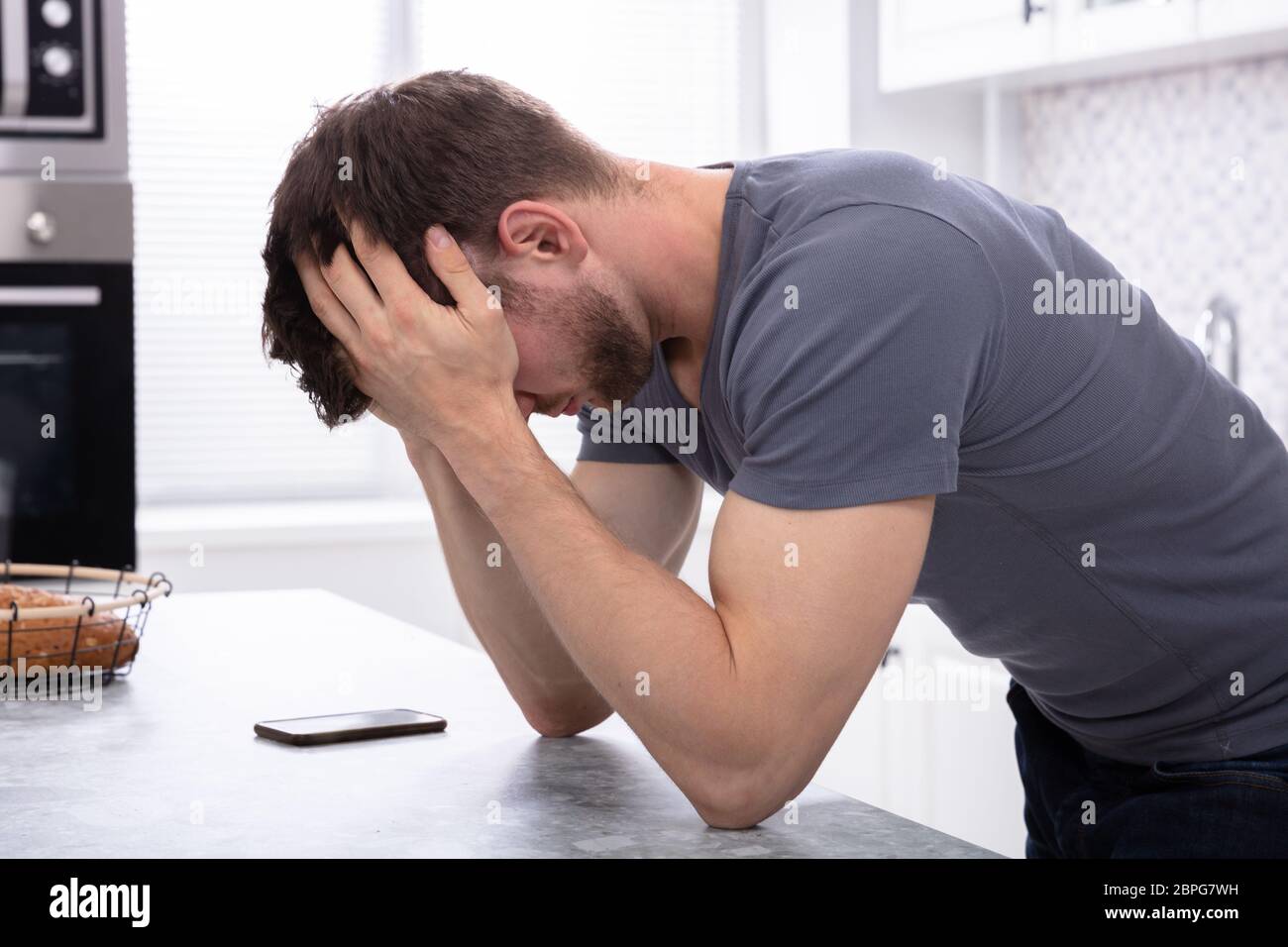 Frustrated Man Covering His Face With Two Hand Sitting In Kitchen Stock ...
