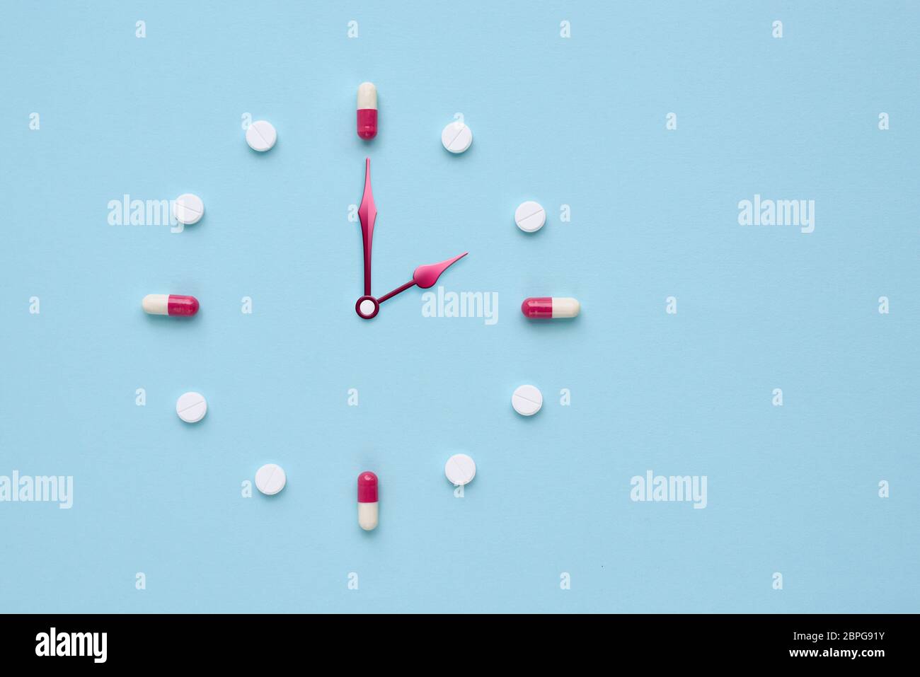 Clock created from pills and capsules on pastel blue background. Right ...