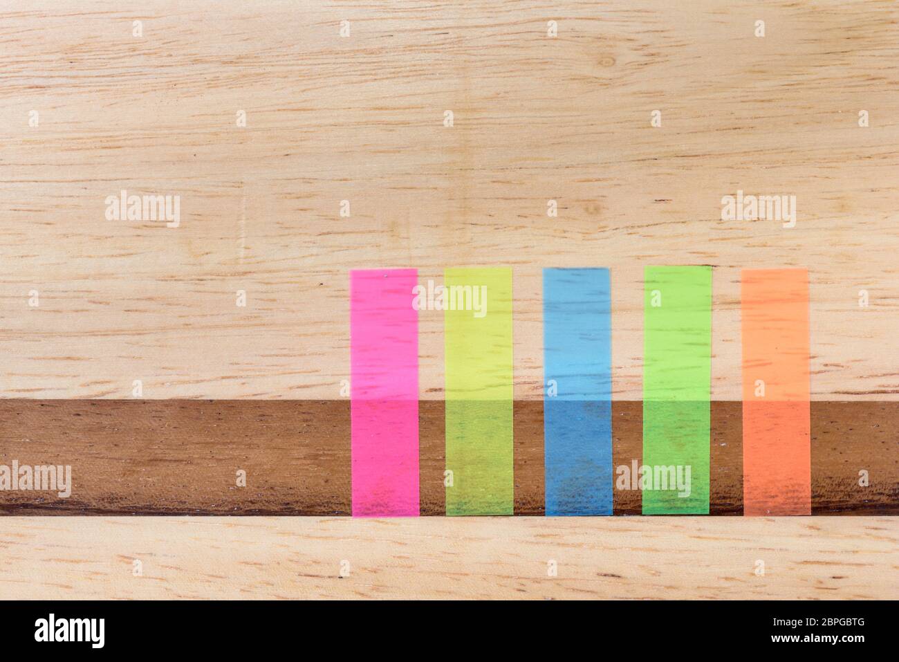 Notes five colours in veritcal on wood background Stock Photo - Alamy