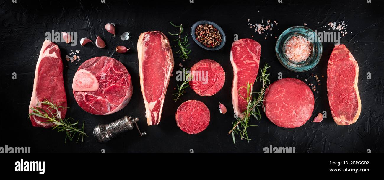 Various cuts of meat, shot from above on a dark background with ...