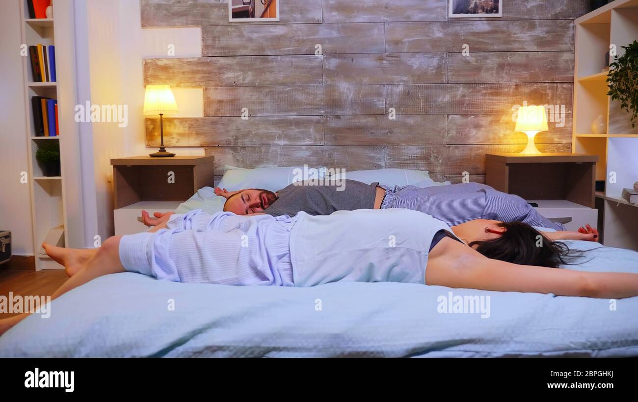 Young married couple falling back on bed. Comfortable bed Stock Photo ...