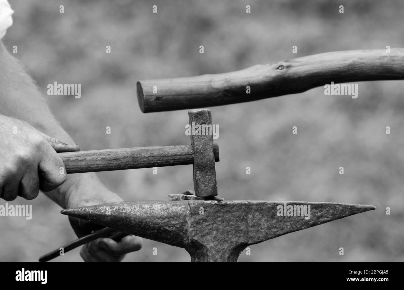 Close-up of man's hand using a rustic hammer to work a piece of metal ...
