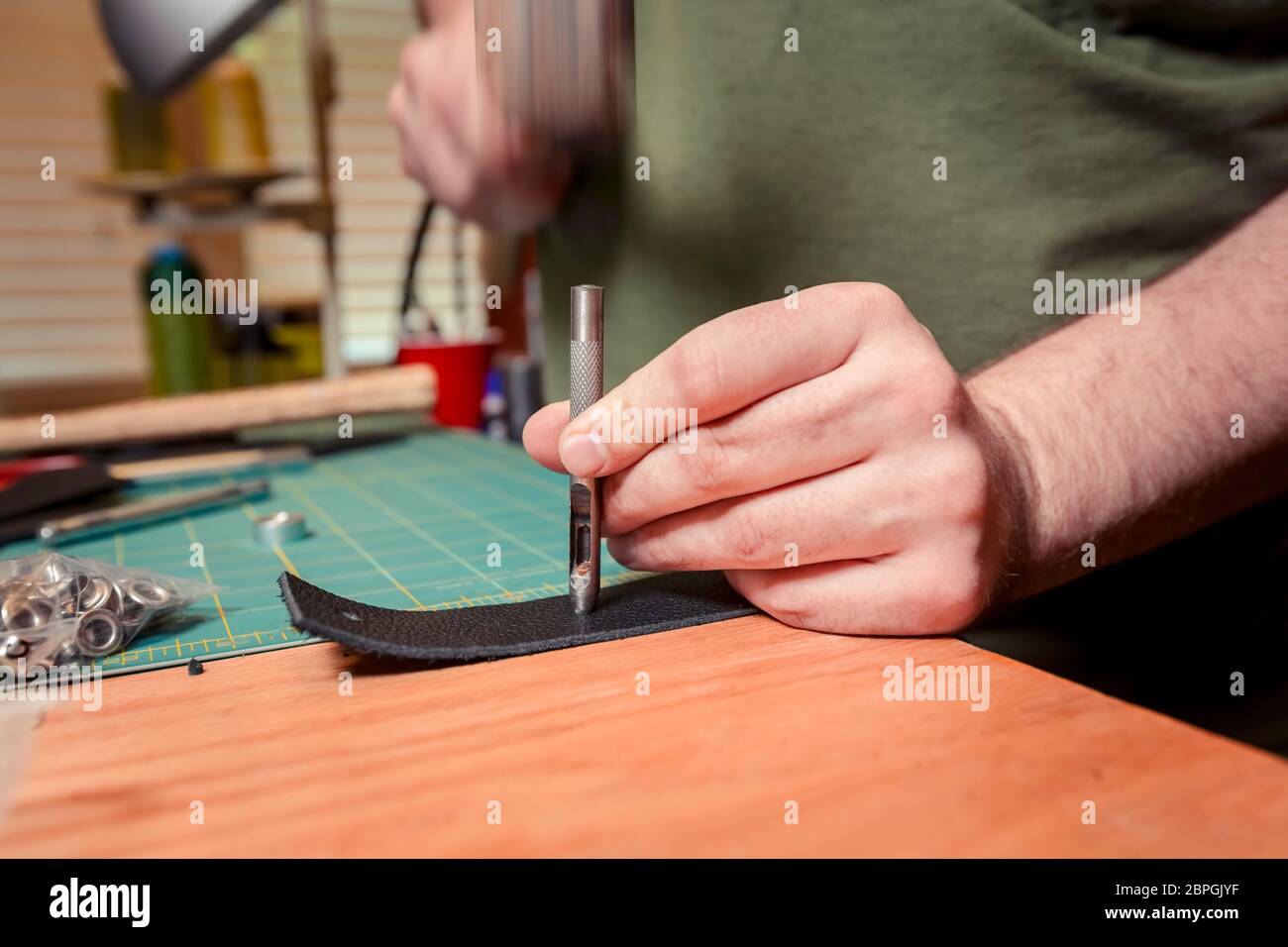 Close up of hands punching hole for a rivet into leather strip Stock ...