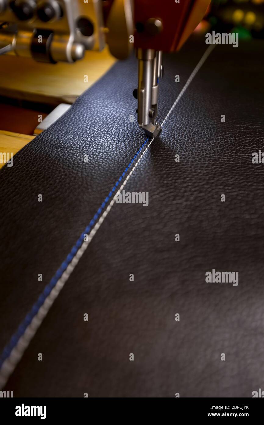 Leather on industrial sewing machine showing white and blue stitches ...