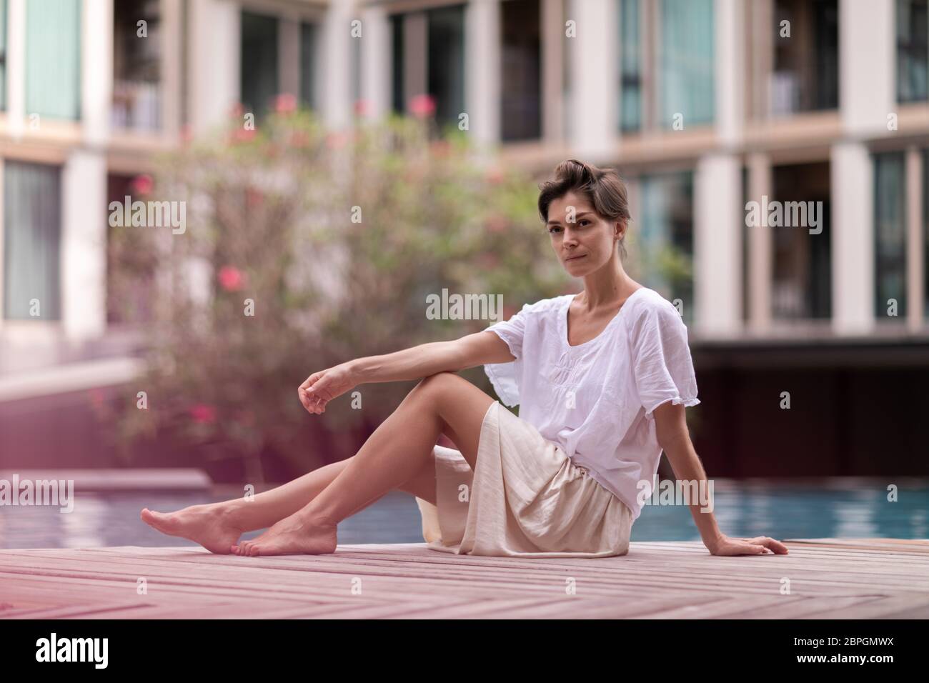 Pretty slim woman with sort haircut sitting near pool outdoors in ...